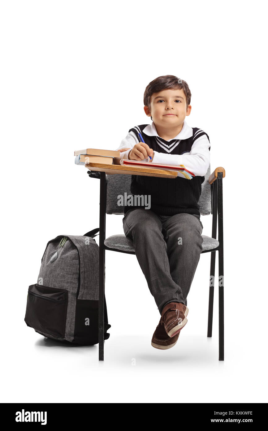 Little schoolboy sitting in a school chair isolated on white background ...