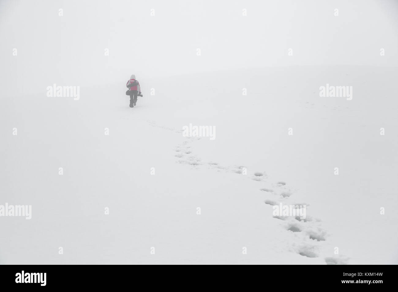 Photographer climbs the snow-covered slope of the mountain Stock Photo ...