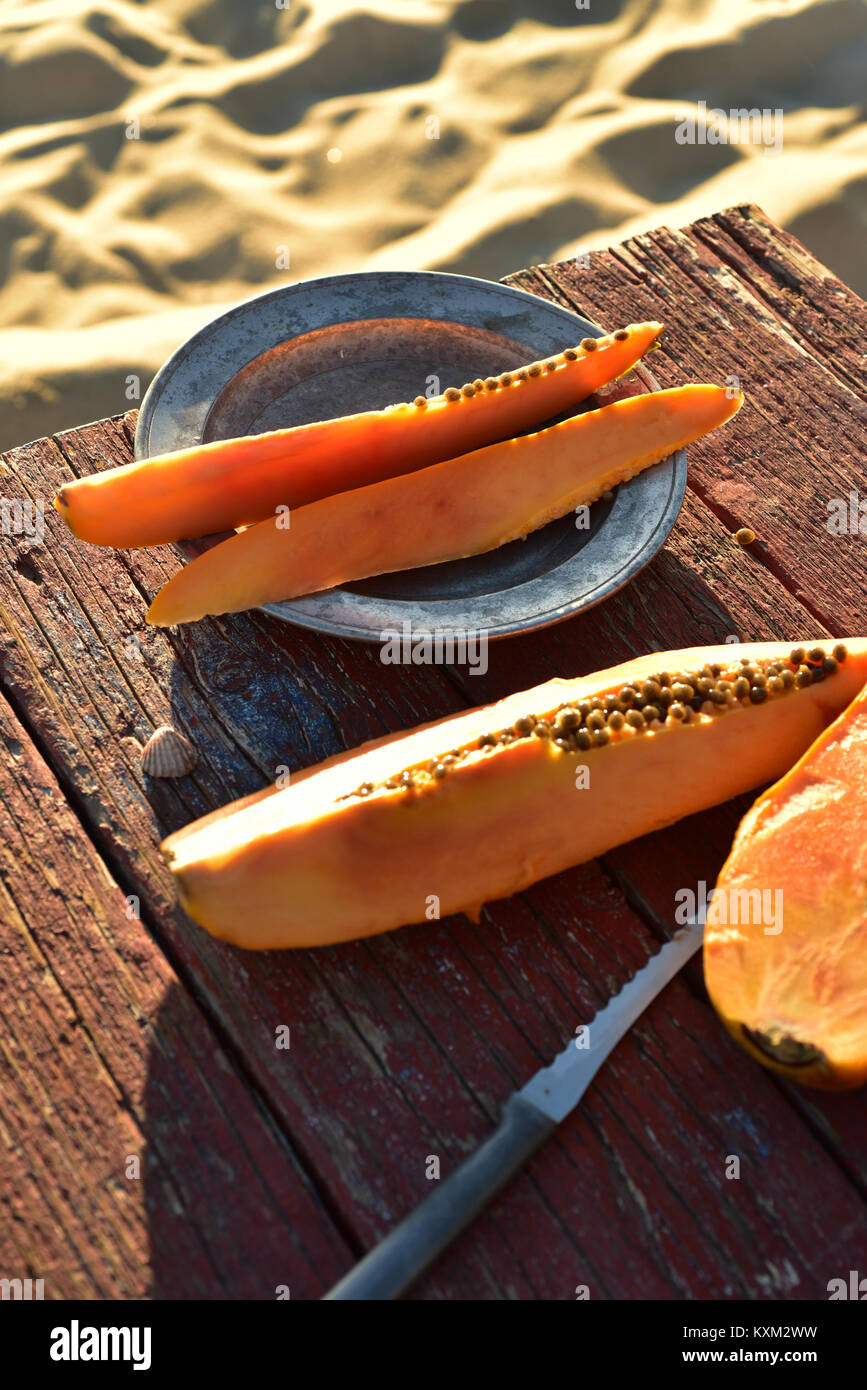 fresh cut papaya fruit on rustic wood table sand beach shore Baja ...