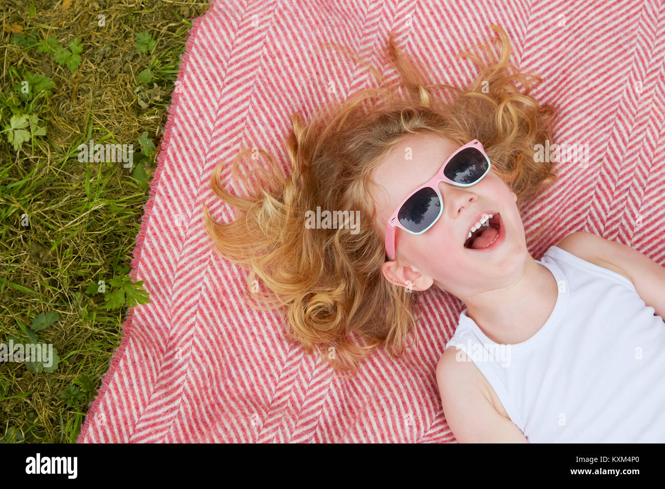 Overhead portrait of girl with blond hair and sunglasses posing on ...
