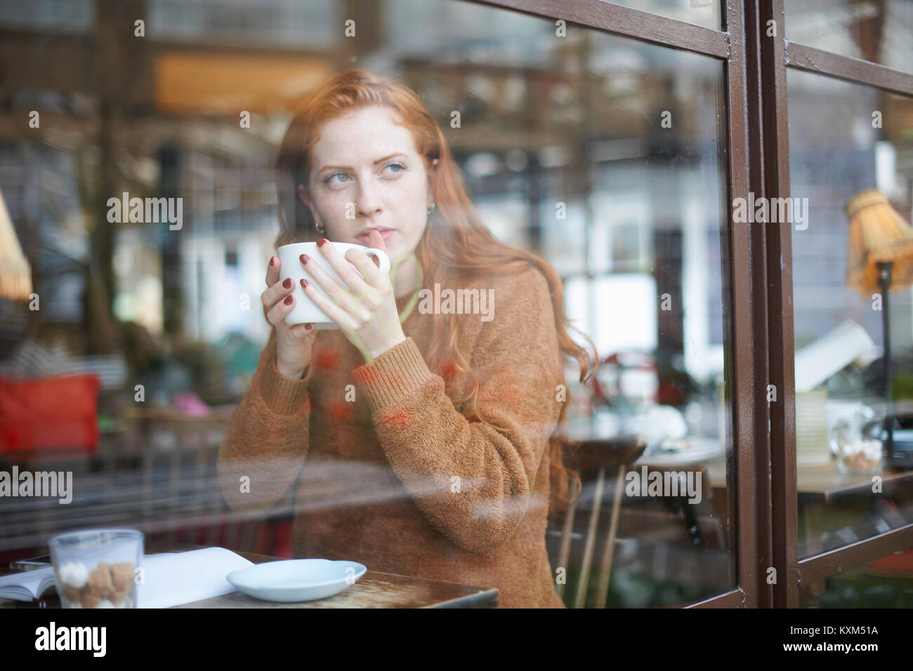 View through window of woman in coffee shop holding cup Stock Photo - Alamy