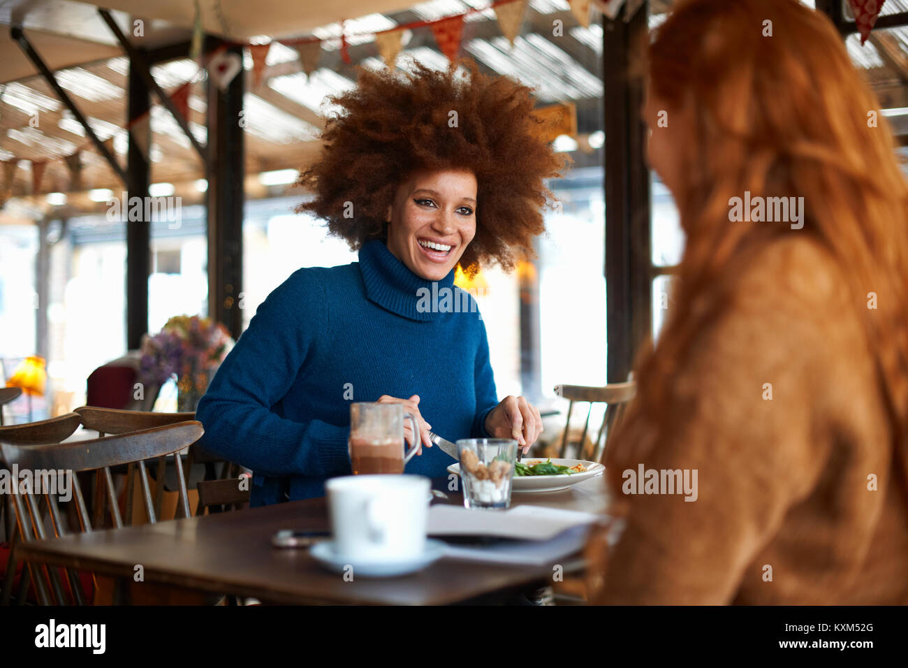 Woman dining in cafe with friend,smiling Stock Photo - Alamy