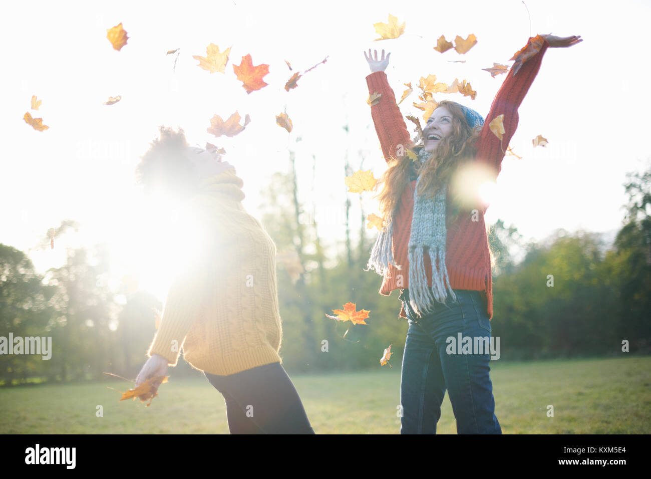 Friends throwing autumn leaves in air Stock Photo - Alamy