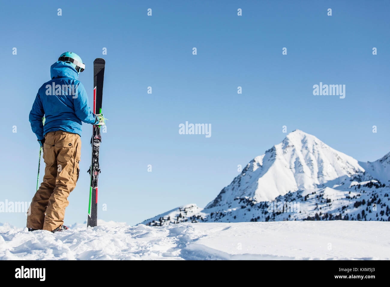 Skier standing in snow,holding skis,looking at mountain,rear view Stock ...