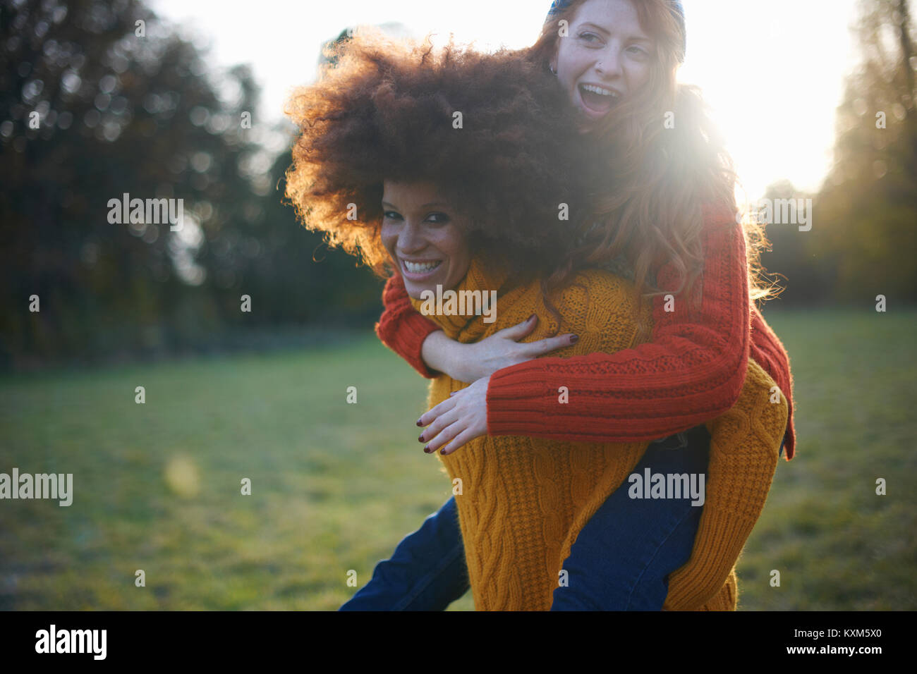 Two young women,in rural setting,young woman giving friend piggyback ...