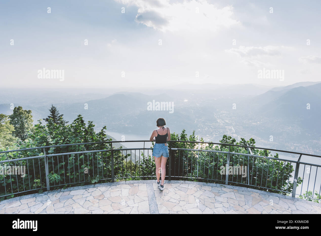 Rear view of young woman on viewing platform looking out at Lake Como ...