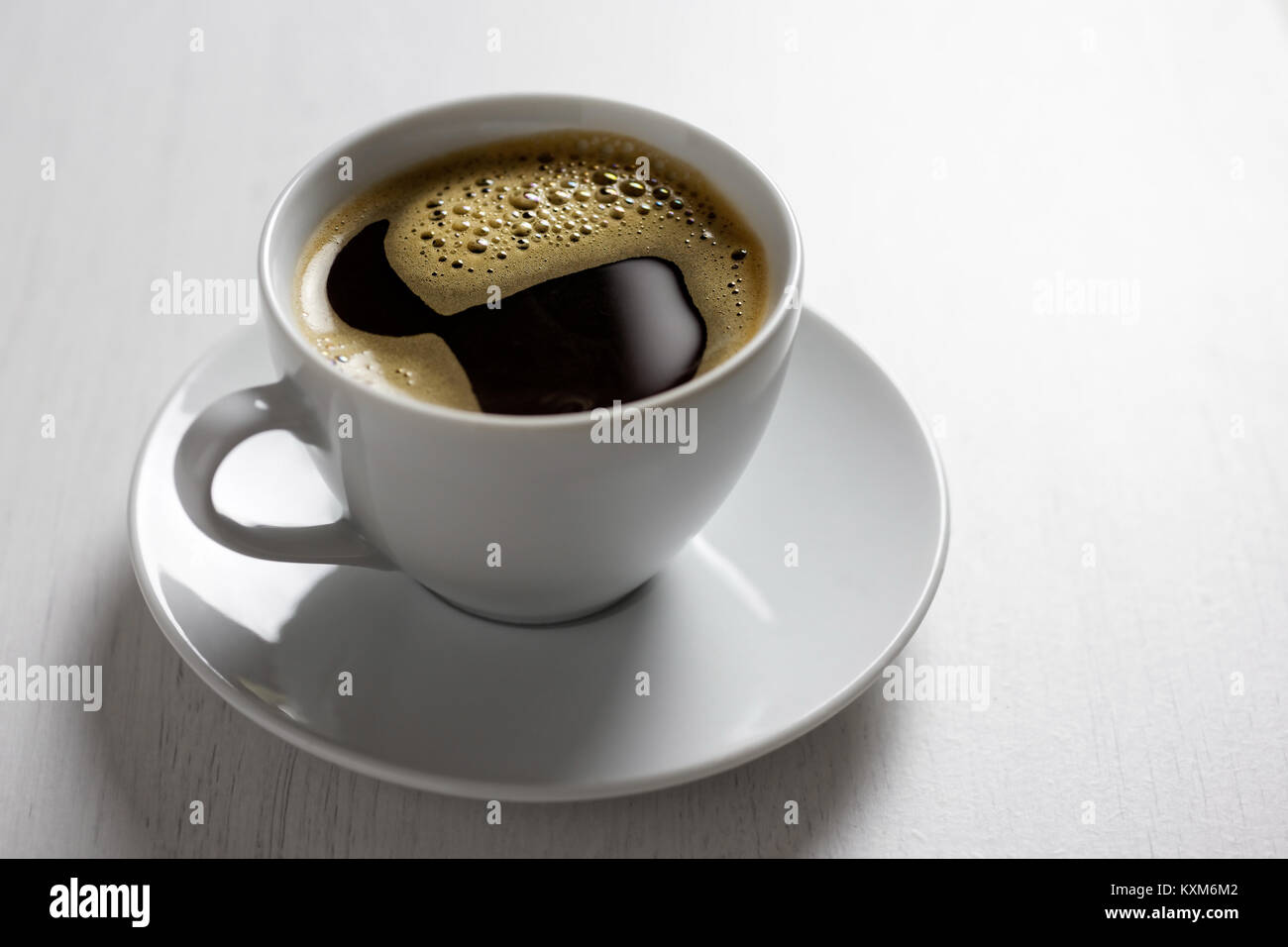 Freshly poured black coffee with froth in white ceramic cup isolated on ...