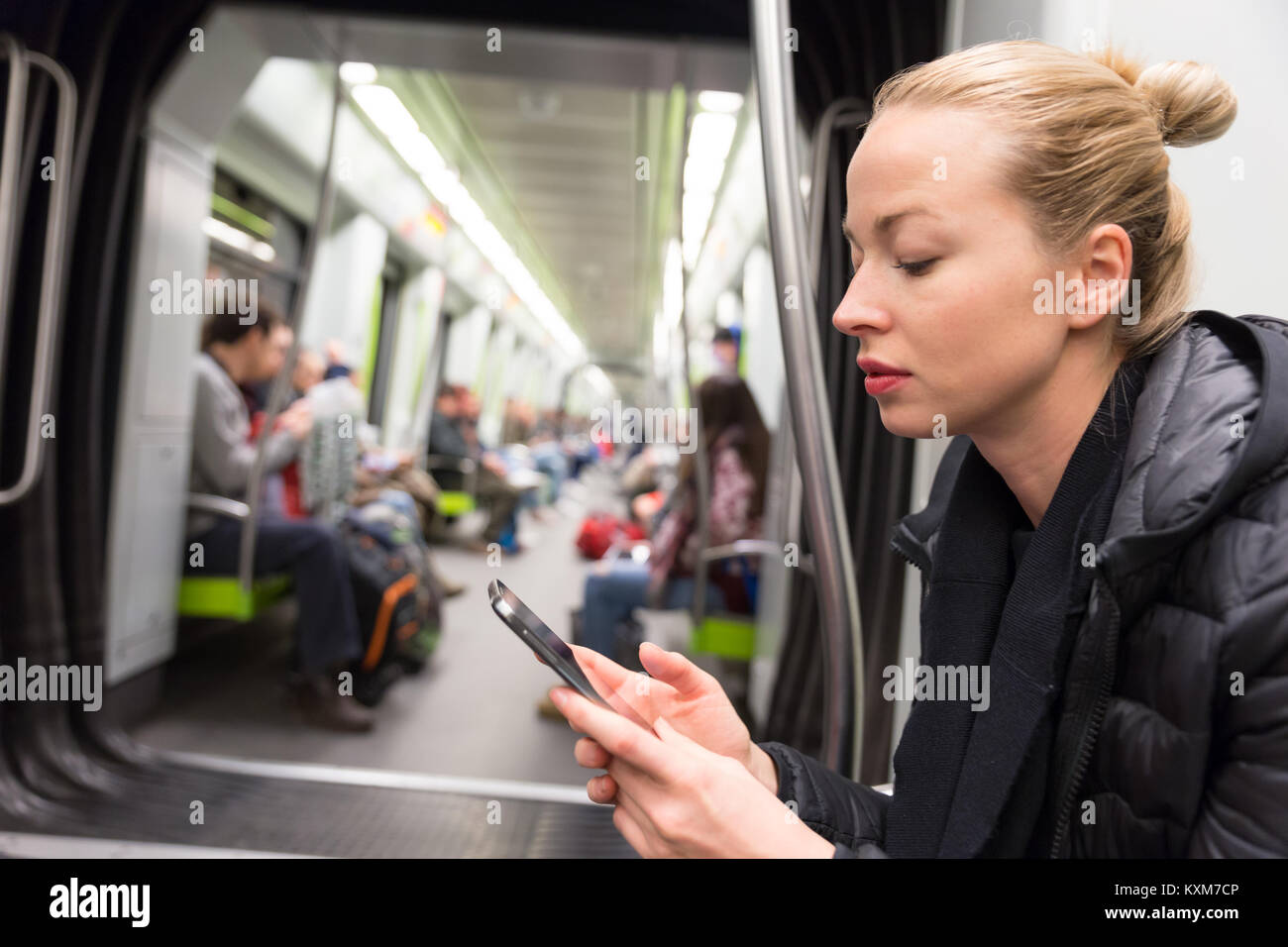 Young girl reading from mobile phone screen in metro Stock Photo - Alamy