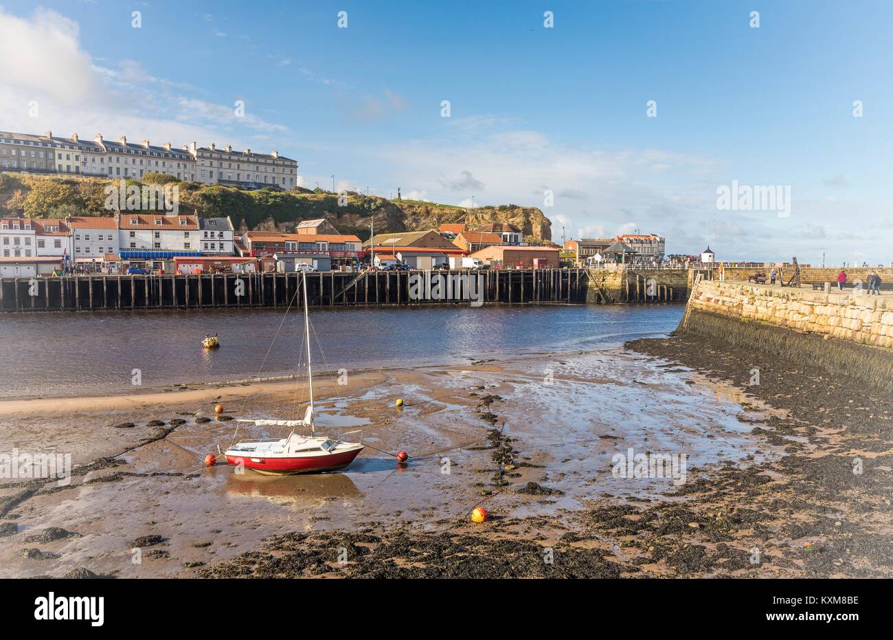 Whitby. Boat around at low tide with town in the background and a blue ...