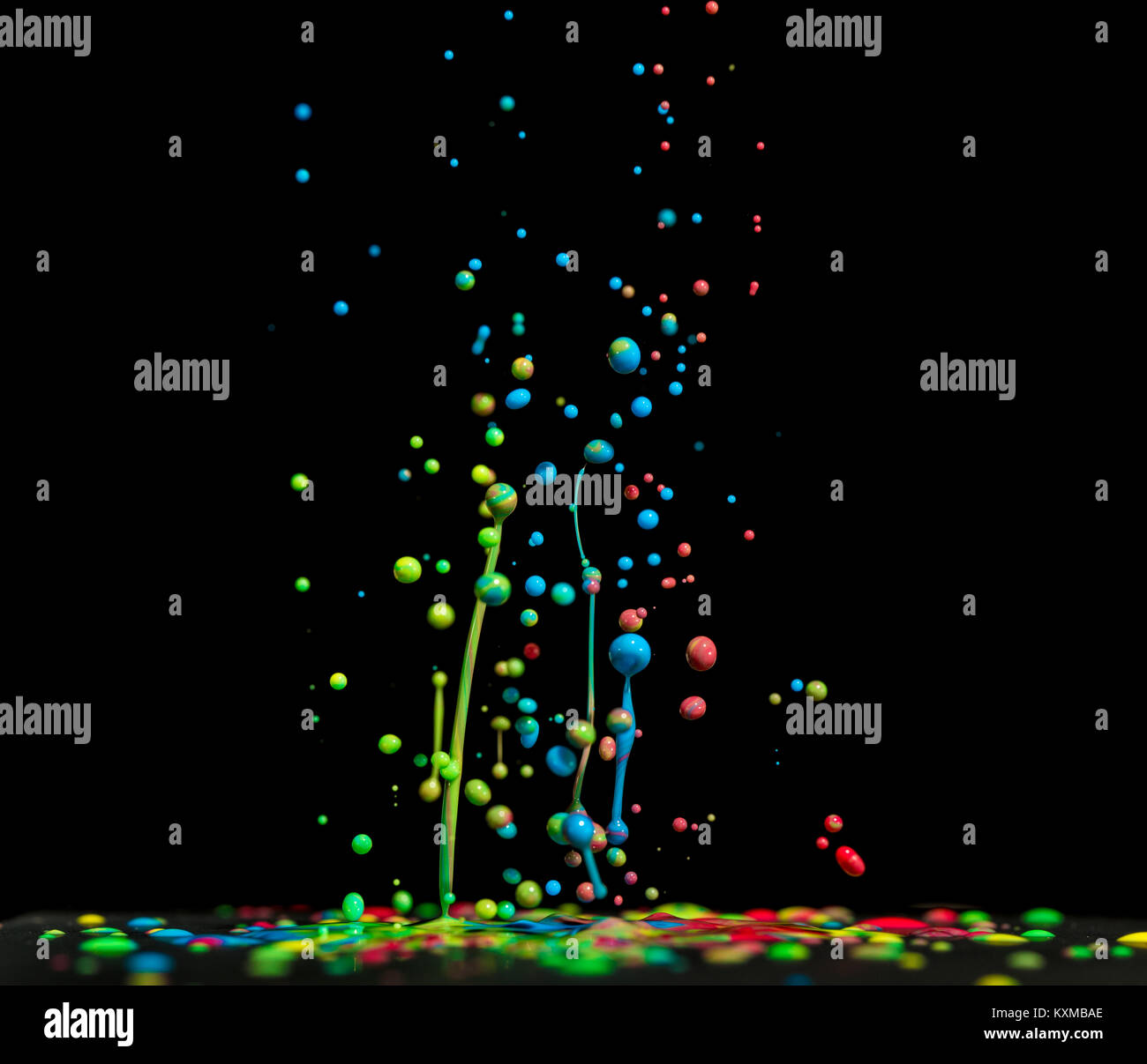 Jumping drops of paint or ink on a black background. multi-colored ...
