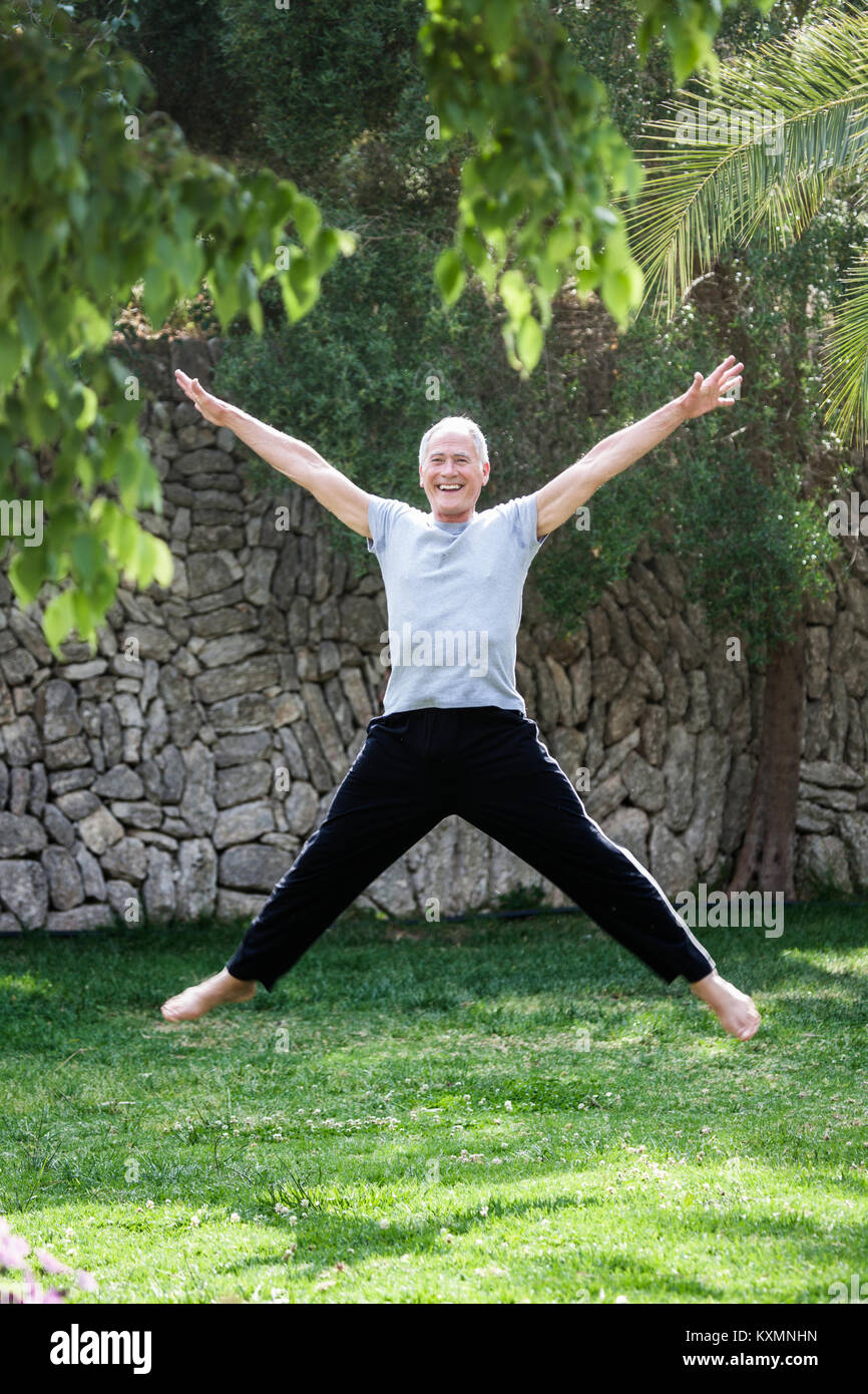 Mature man in mid air doing star jump Stock Photo - Alamy