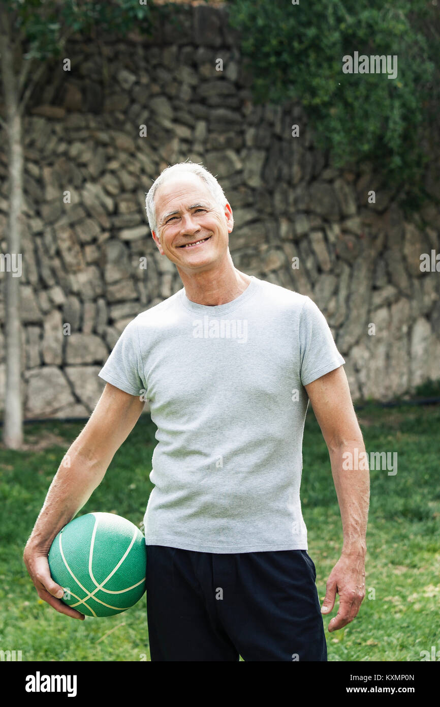Portrait of man holding basketball looking at camera smiling Stock ...