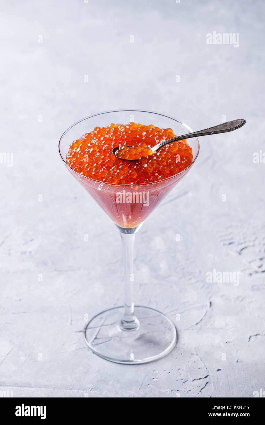 Cocktail glass of red caviar with vintage spoon over gray texture ...