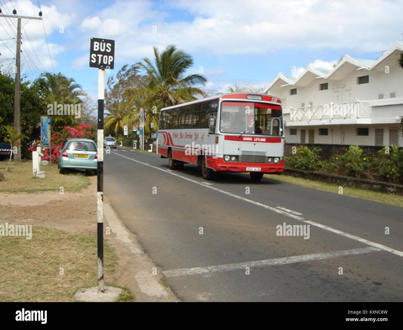 This image depicts a bus and bus stop in Mauritius. The scene shows a ...