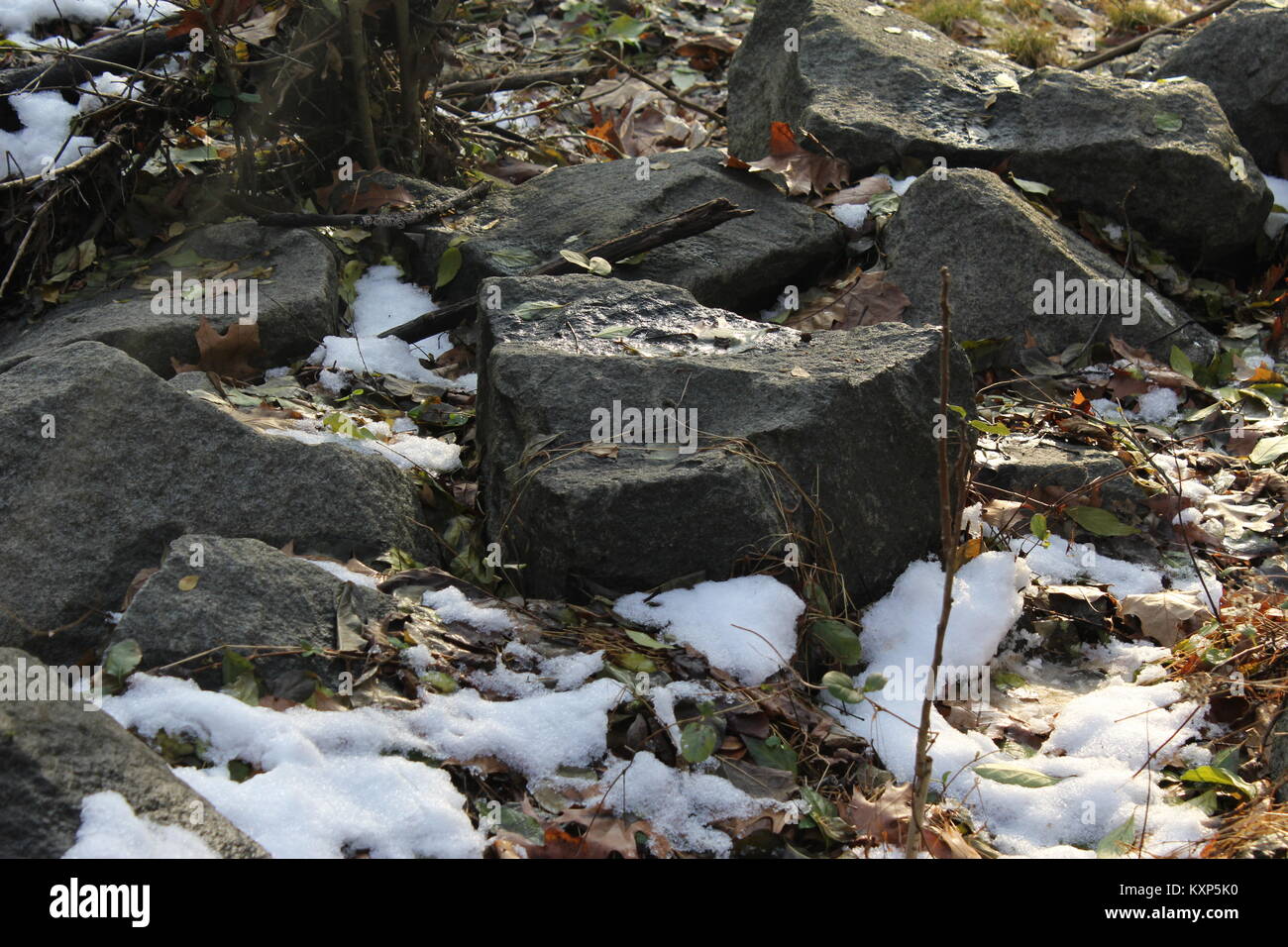 Cold rocks sitting in patchy snow Stock Photo - Alamy