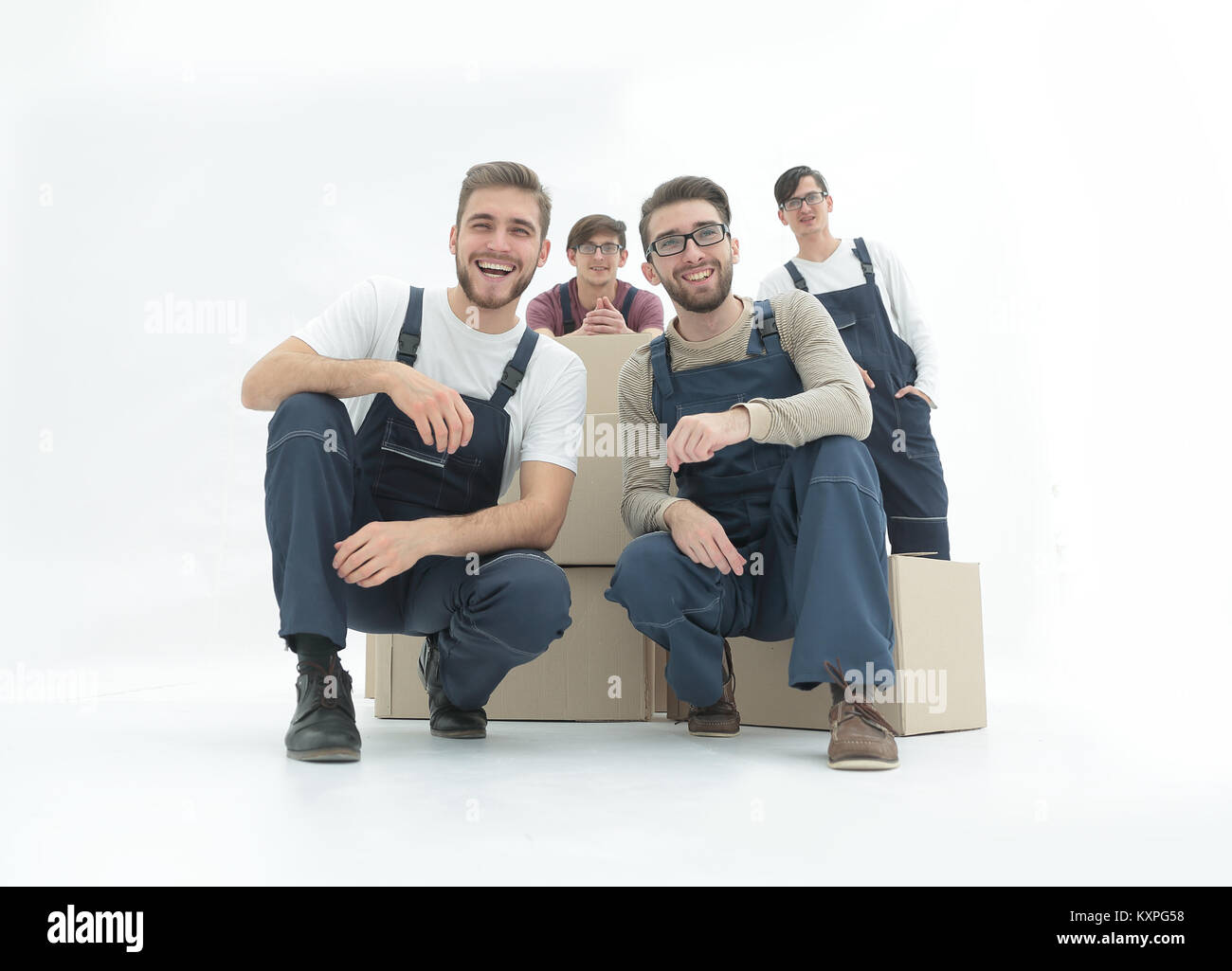 Smiling young delivery men holding stack of boxes. Isolated on w Stock ...