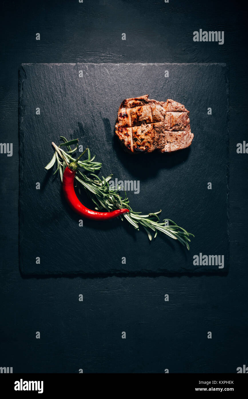 top view of gourmet grilled steak with rosemary and chili pepper on ...