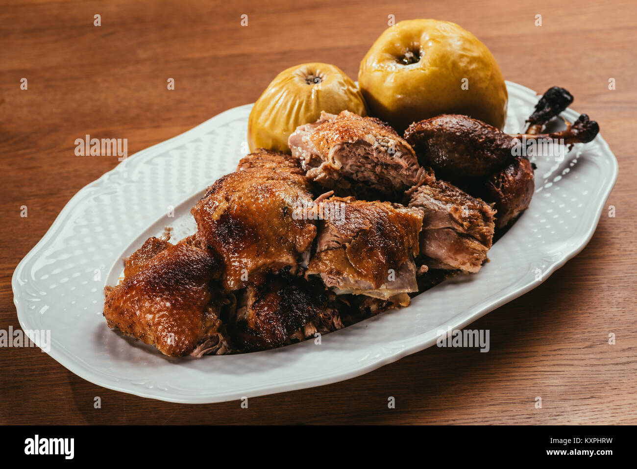fried duck pieces laying on plate with marinated apples over wooden ...