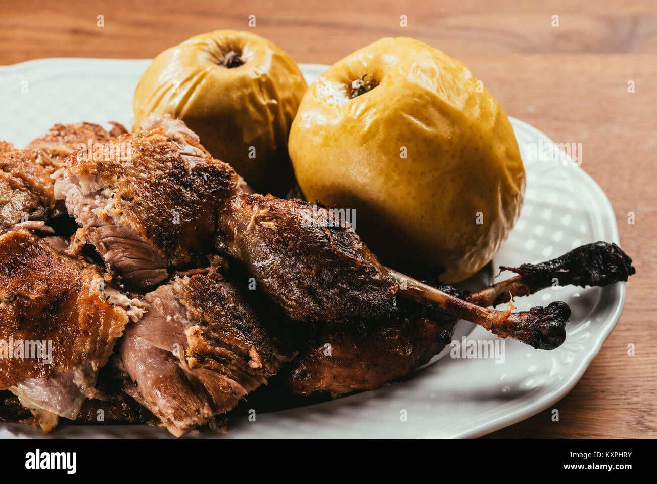 fried duck pieces laying on plate with marinated apples over wooden ...