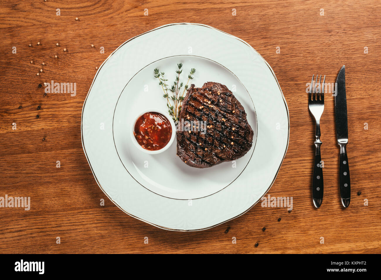 Top view of grilled steak with pepper, rosemary and sauce on white ...