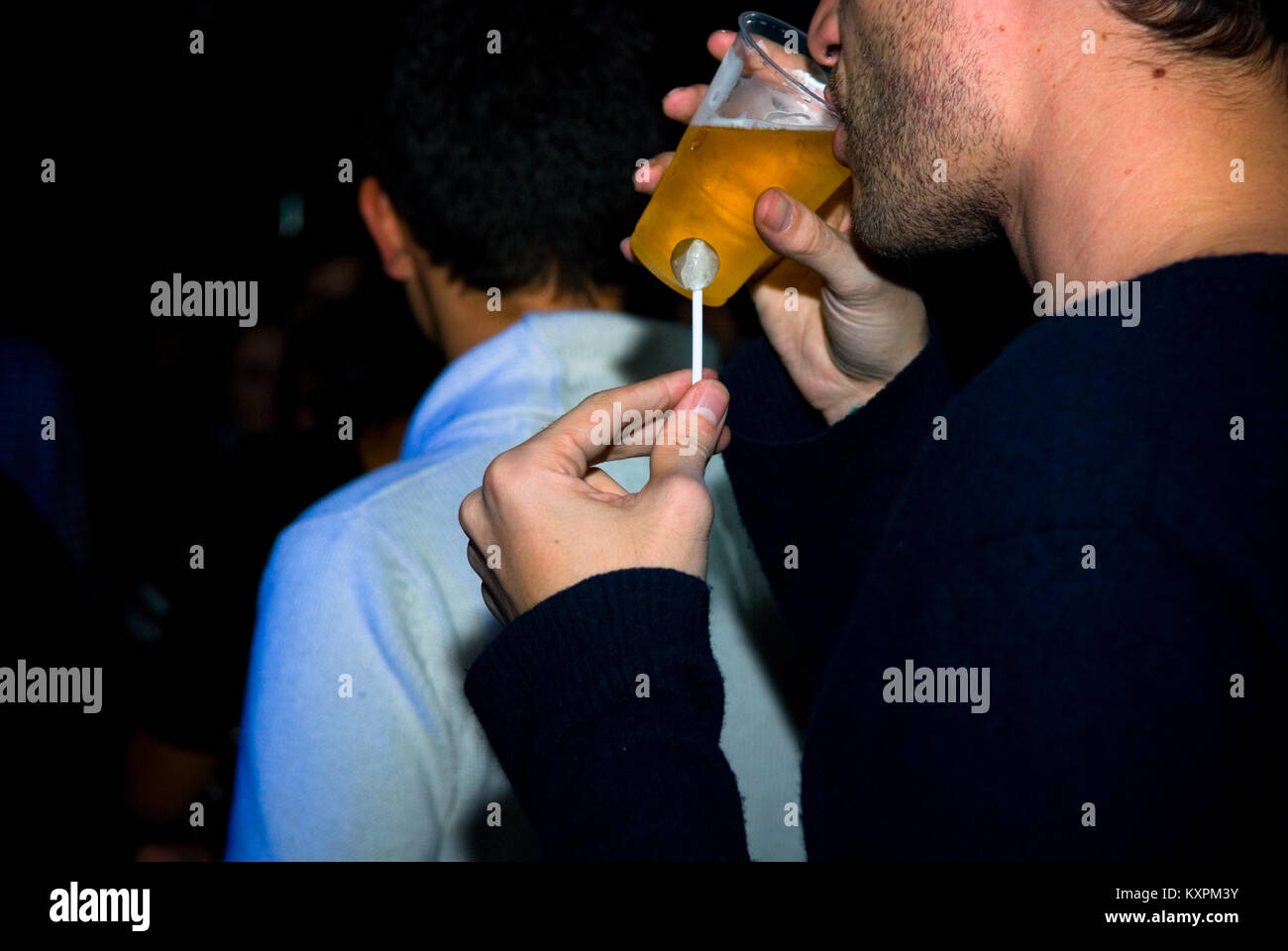 a cropped view of a young male in his twenties drinking lager from a ...