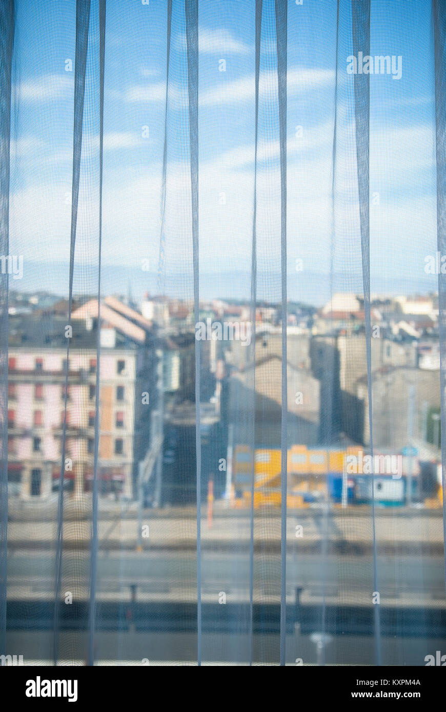 a shot through a window with a net curtain looking over part of Geneva ...