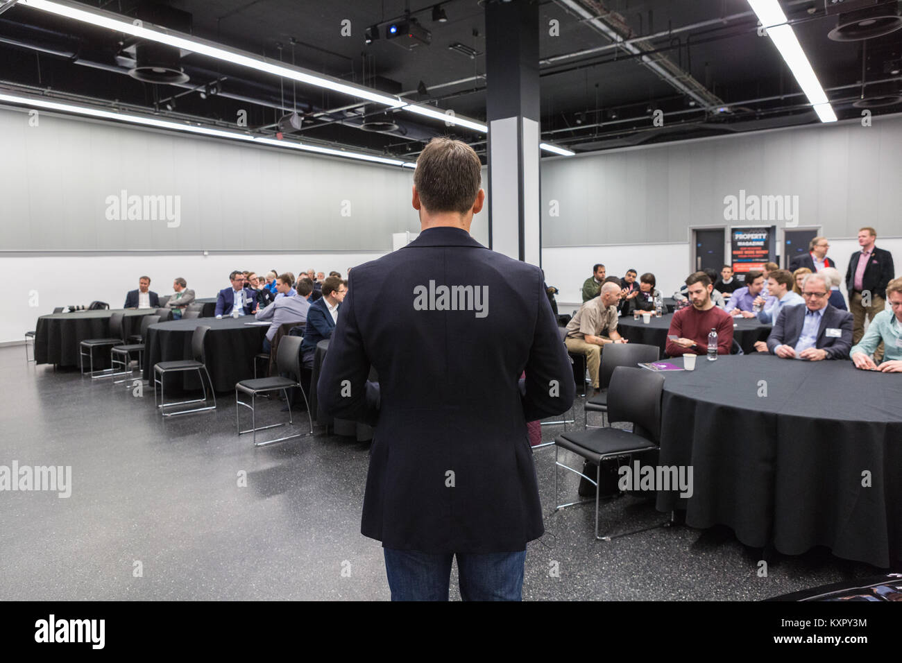 Entrepreneur giving seminar to a large hall of businessmen and women ...