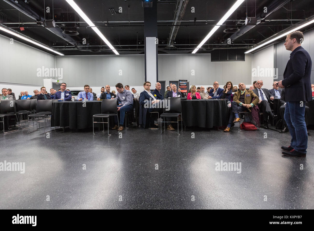 Entrepreneur giving seminar to a large hall of businessmen and women ...