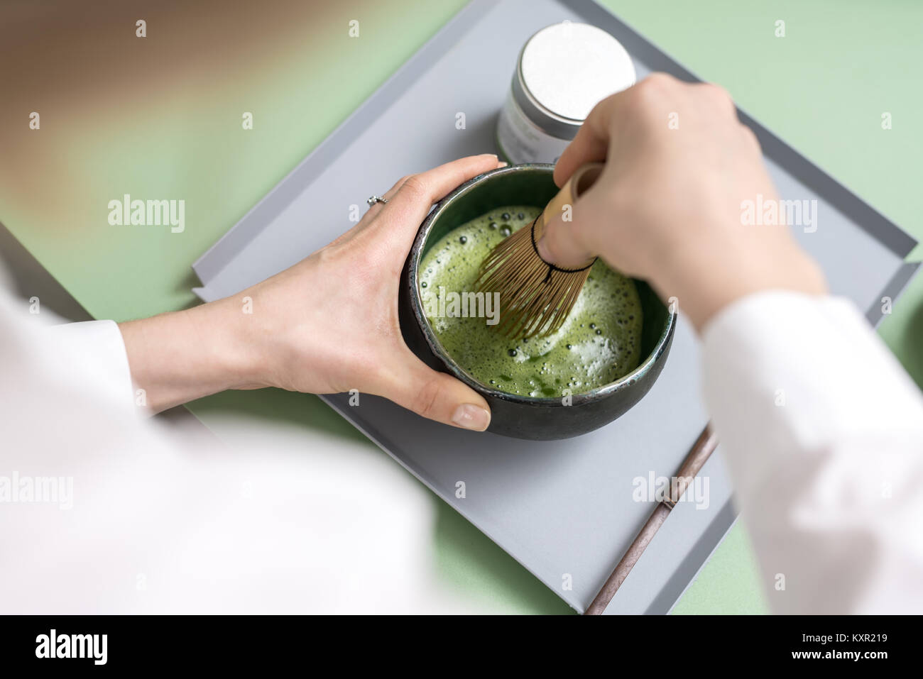 Pretty girl prepares a chinese matcha green tea on the green metal ...