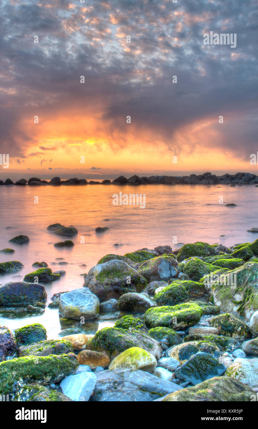 Dramatic sea sunset in Italy with rocks and clouds Stock Photo - Alamy