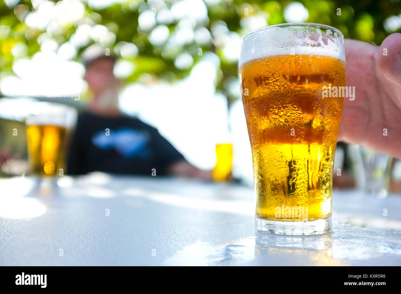 man's hand grabbing a glass of beer at an outdoor table Stock Photo - Alamy