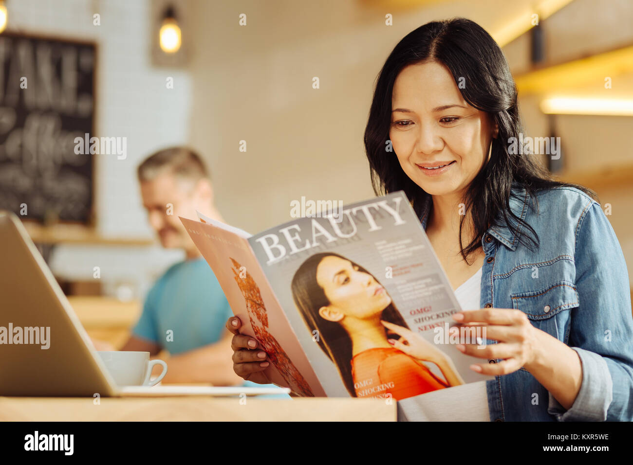 Smiling woman reading a fashion magazine Stock Photo - Alamy
