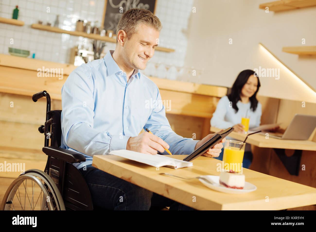 Smiling disabled man working from a cafe Stock Photo - Alamy