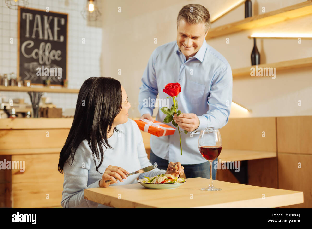 Cheerful man giving rose and present to his woman Stock Photo - Alamy