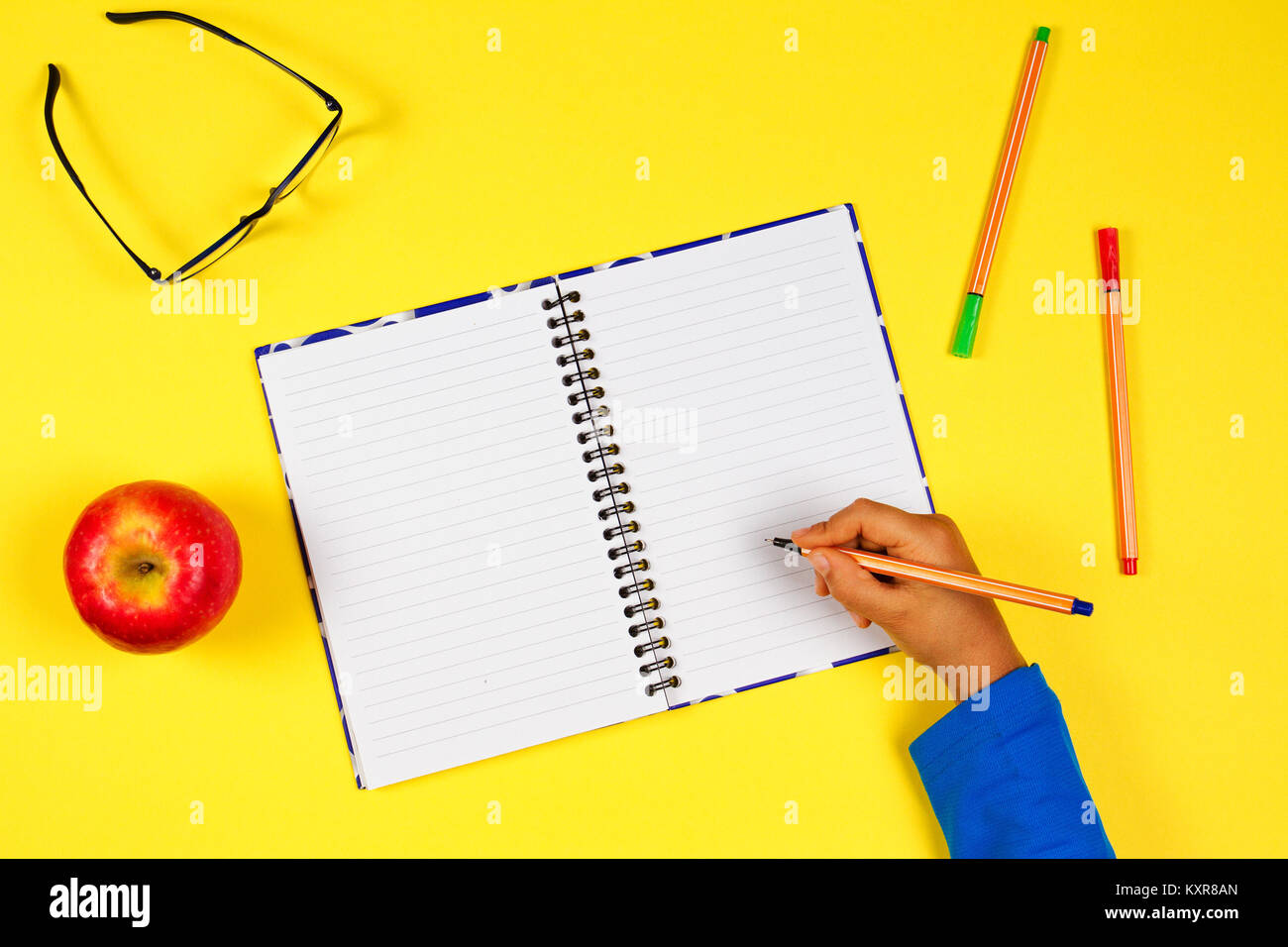 Colorful school workspace. Kid hand with open notebook, pen, glasses ...
