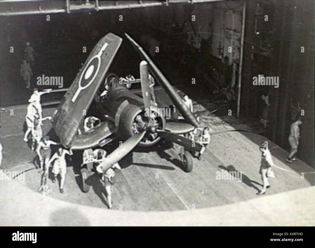 The image shows a Corsair aircraft being moved on an elevator aboard ...