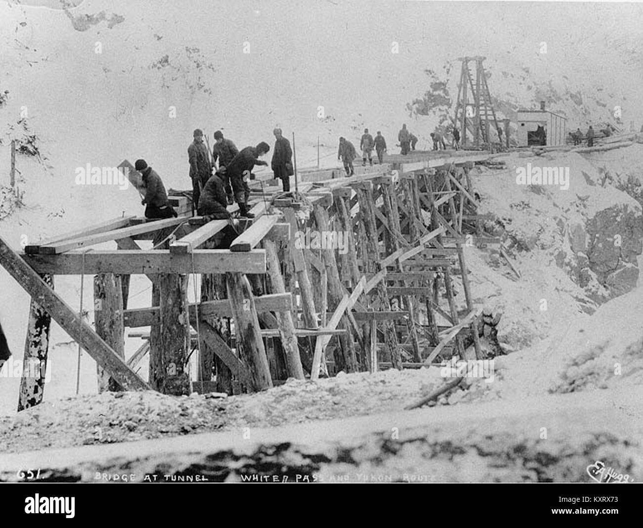 Photograph showing workers constructing a wooden trestle bridge span ...