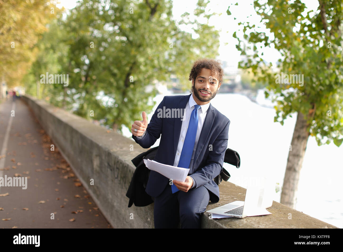 Mulatto man working near river with laptop Stock Photo - Alamy