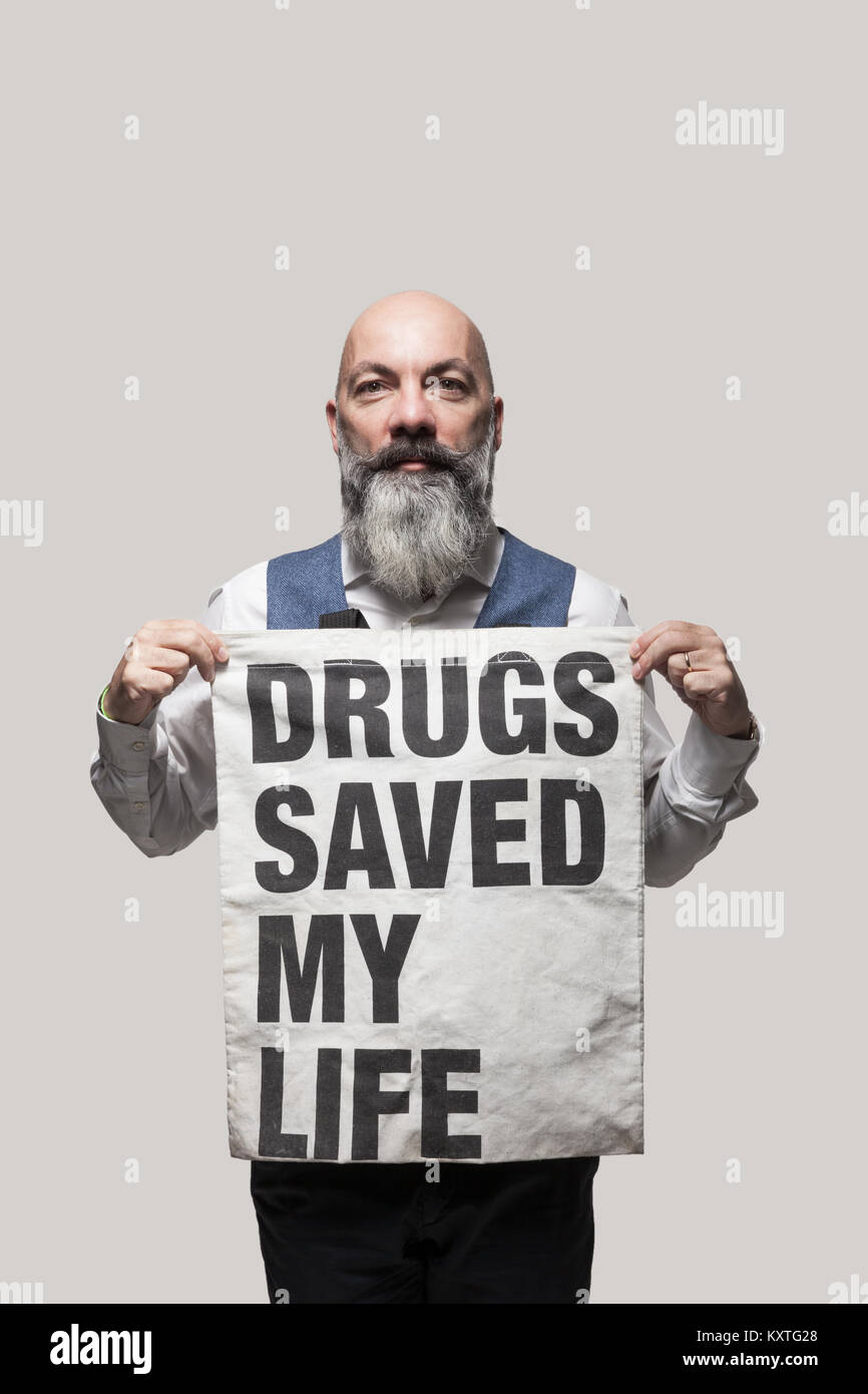 Man shows poster with a slogan, isolated on gray background. Drugs ...