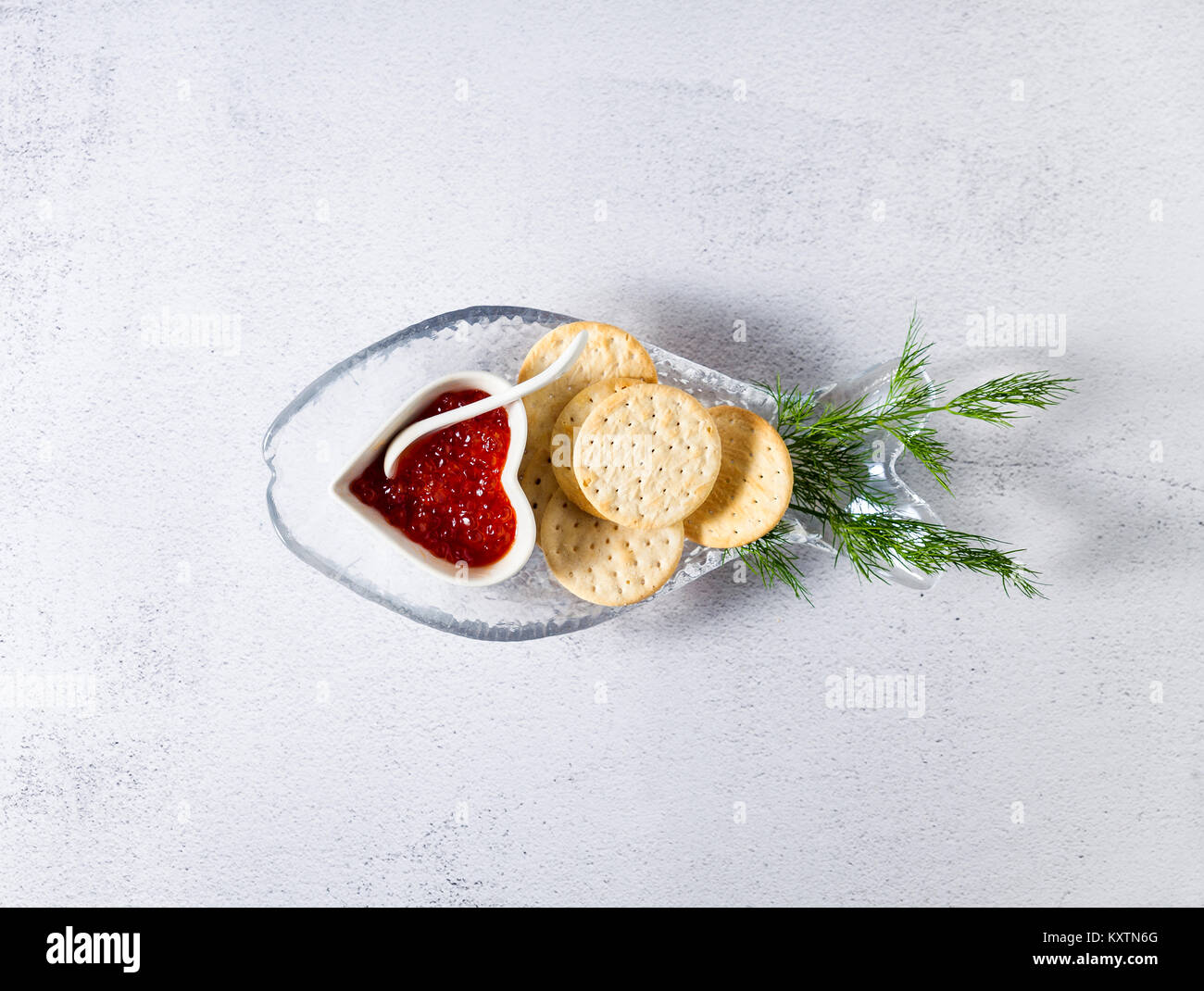 a saucer with red caviar and a cracker for a snack and fresh dill in a ...