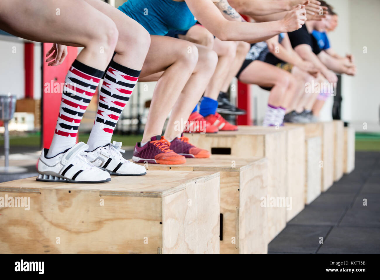 Low section of women performing box jumps with friends in fitness ...