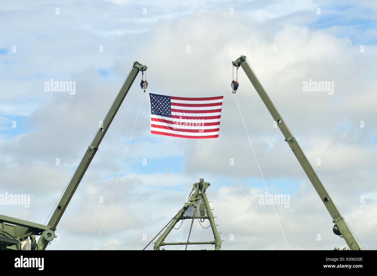 American flag suspended from 2 military truck boom arms Stock Photo - Alamy