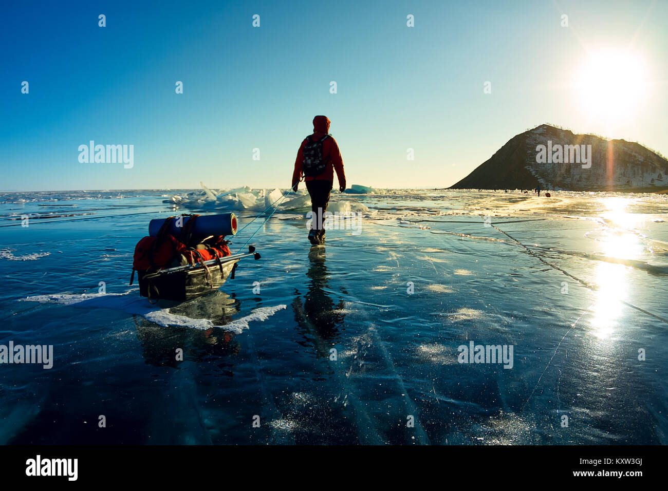 Woman with a sledge and trekking pole is on the ice of Lake Baikal ...