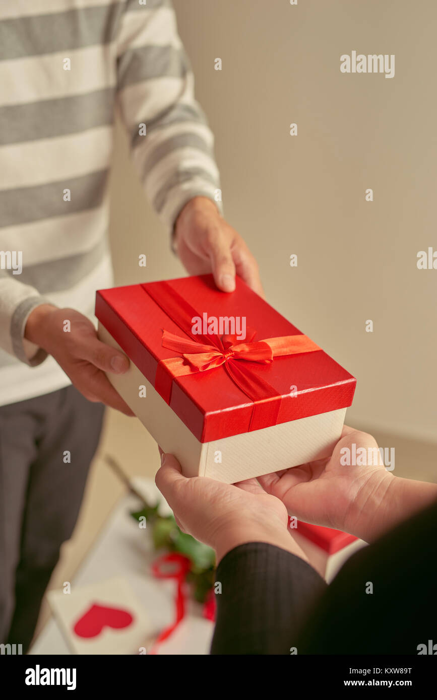 Hands giving and receiving a red present Stock Photo - Alamy