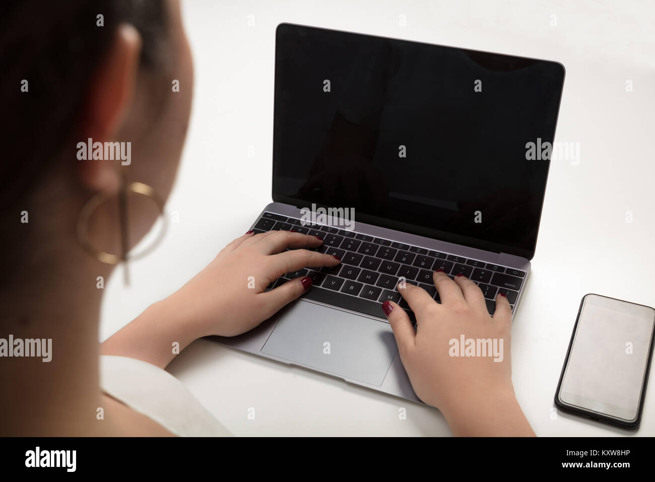 Woman typing on a laptop computer viewed from behind over the shoulder ...