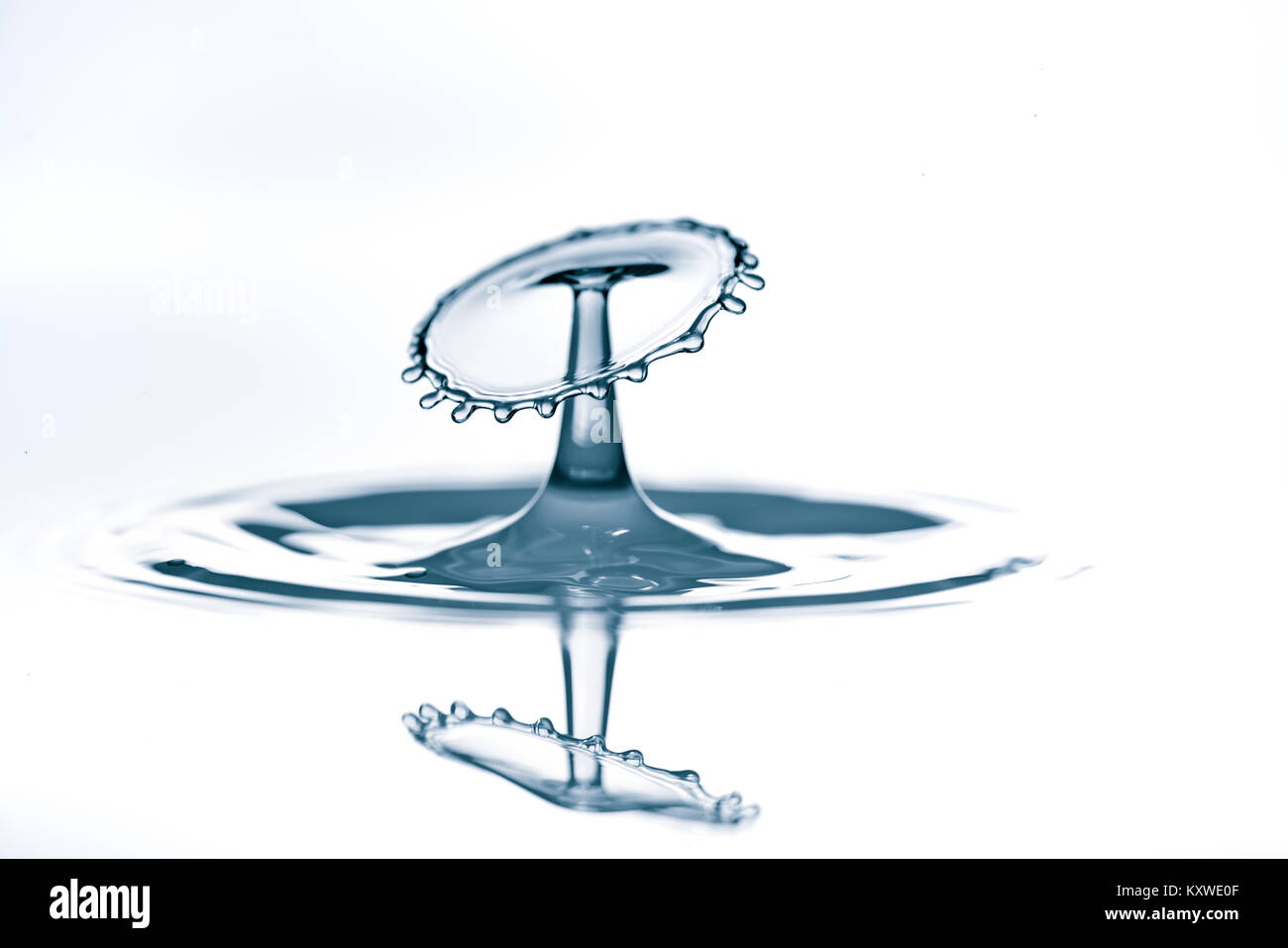Splash and crown on rippled blue liquid or water surface . Water splash ...