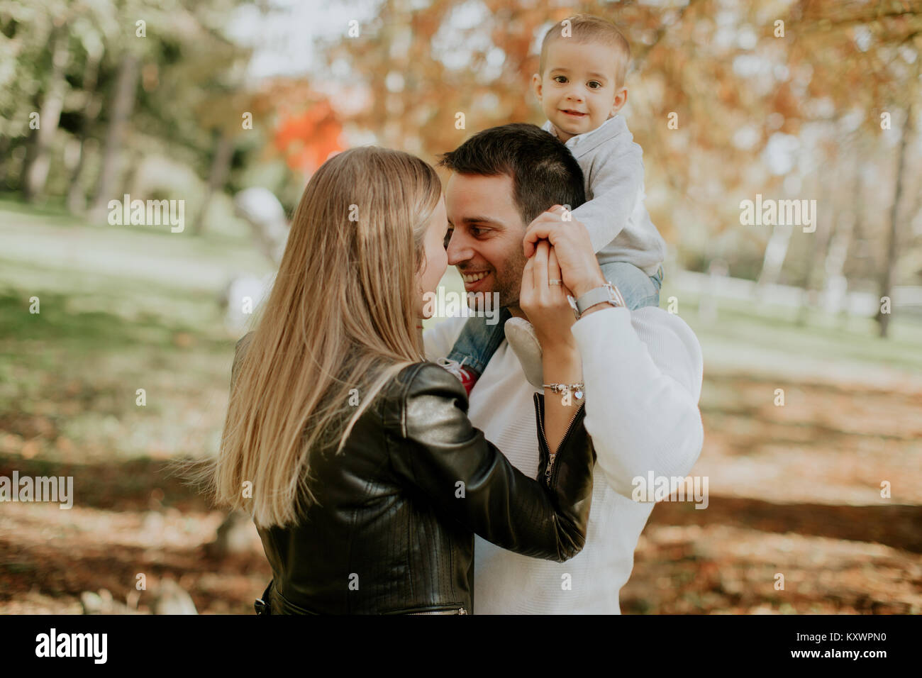 Happy young parents have fun with baby boy in autumn park Stock Photo ...