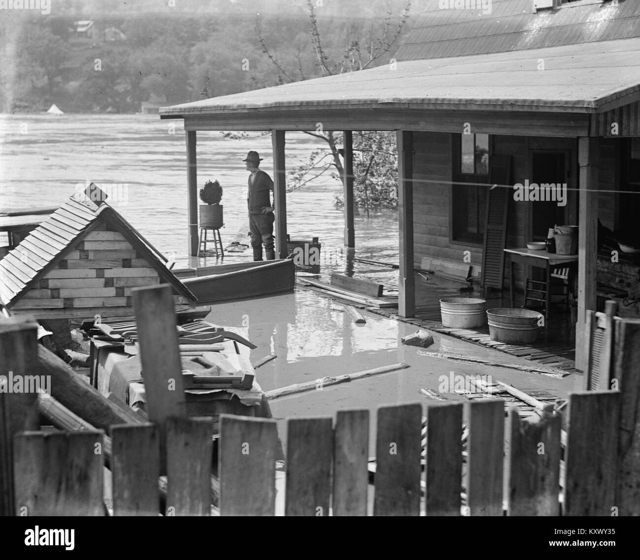 Rising River Floodwaters approach a man who stands on his front porch ...