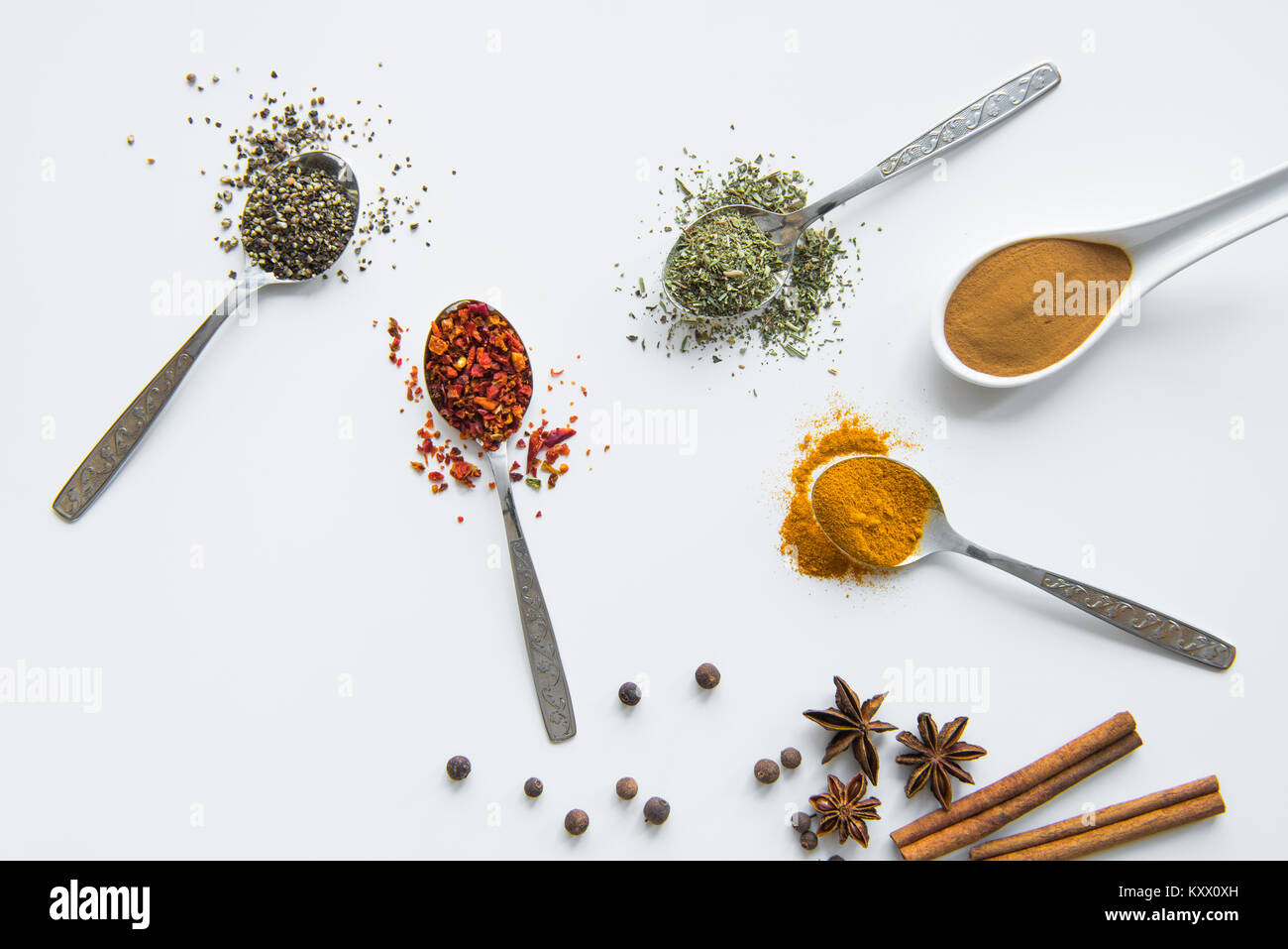Top view of various dried aromatic spices in metal and ceramic spoons ...
