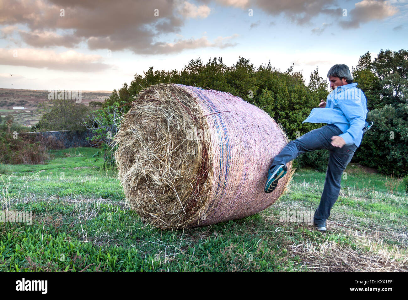 Front view of man who trains with a bale of hay at field against ...